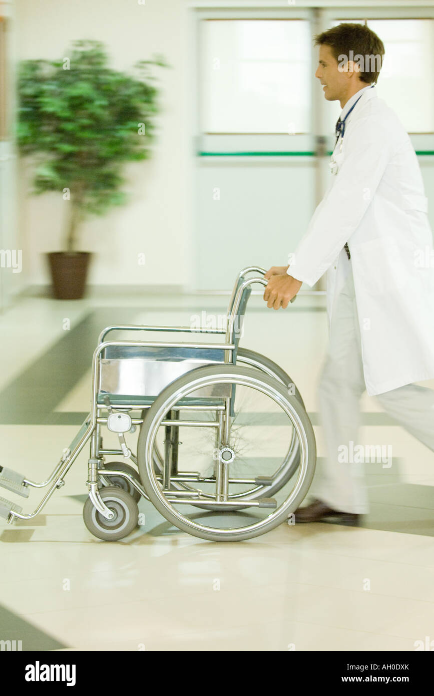 Male doctor pushing empty wheelchair, blurred motion Stock Photo - Alamy