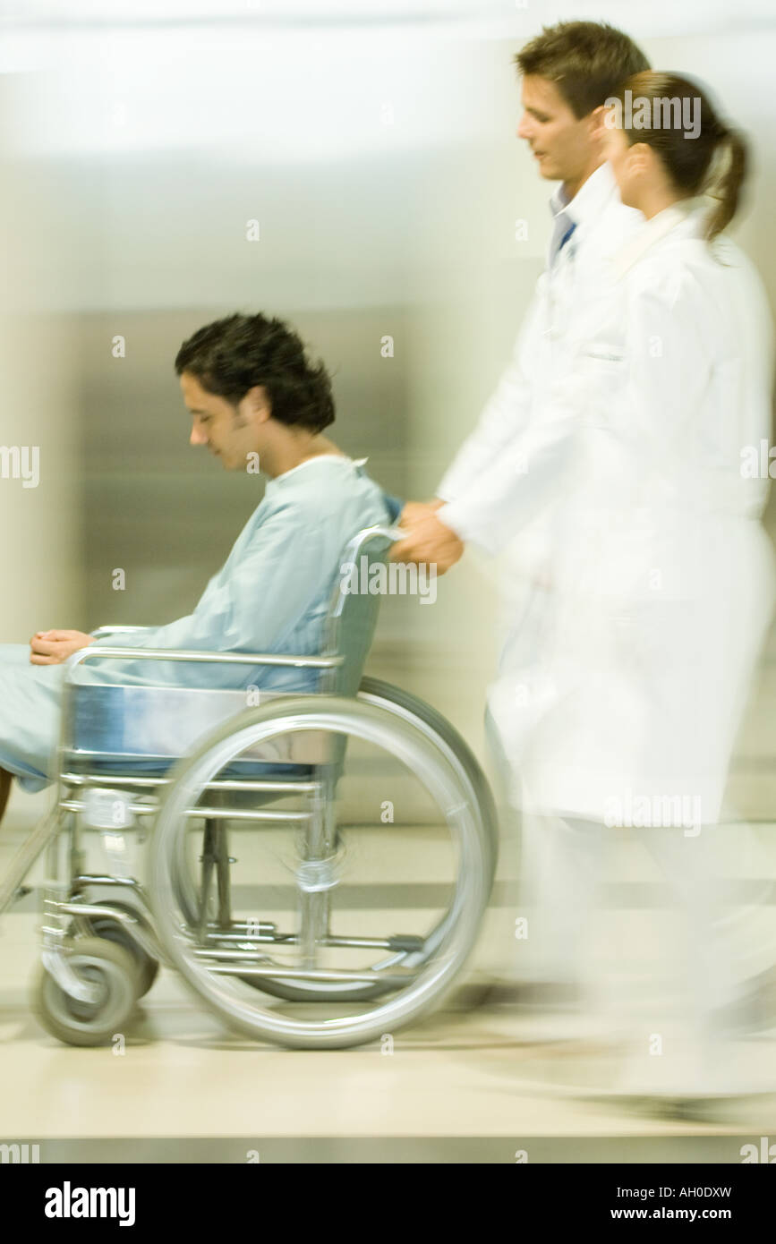 Medical staff pushing man in wheelchair, blurred motion Stock Photo - Alamy