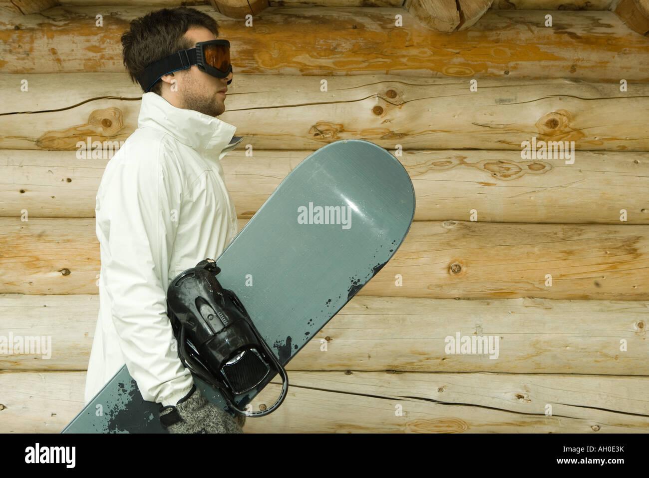 Young man holding snowboard, side view Stock Photo - Alamy