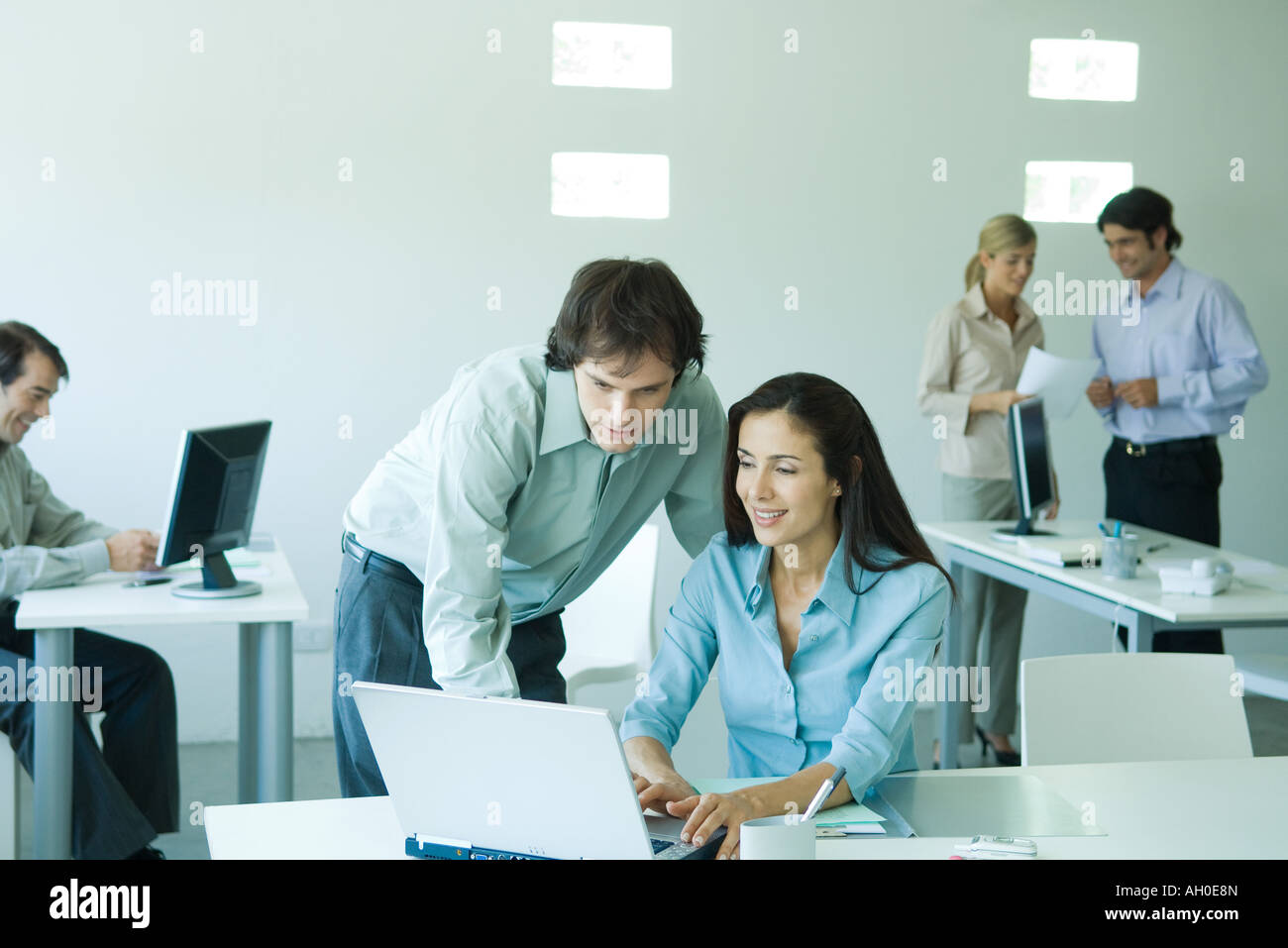 Businessman and businesswoman in office, using laptop computer ...