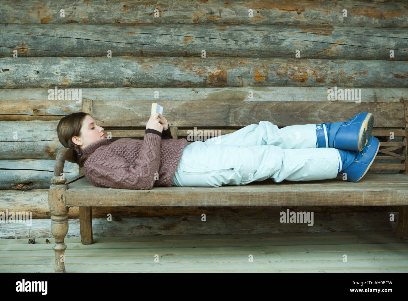 Teenage girl lying on back, reading book, wearing winter clothing Stock ...
