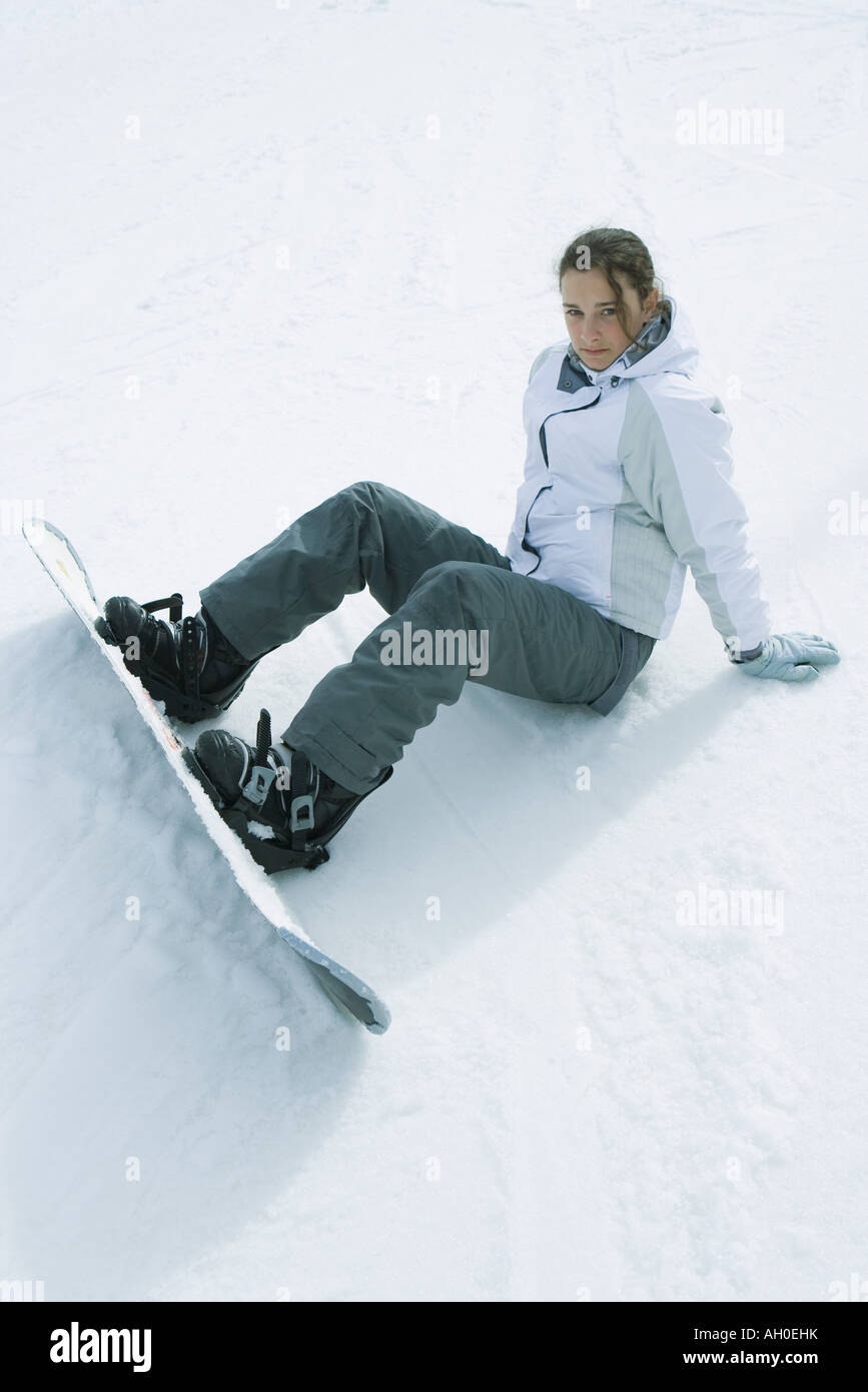 Young snowboarder sitting on the ground, looking at camera Stock Photo ...