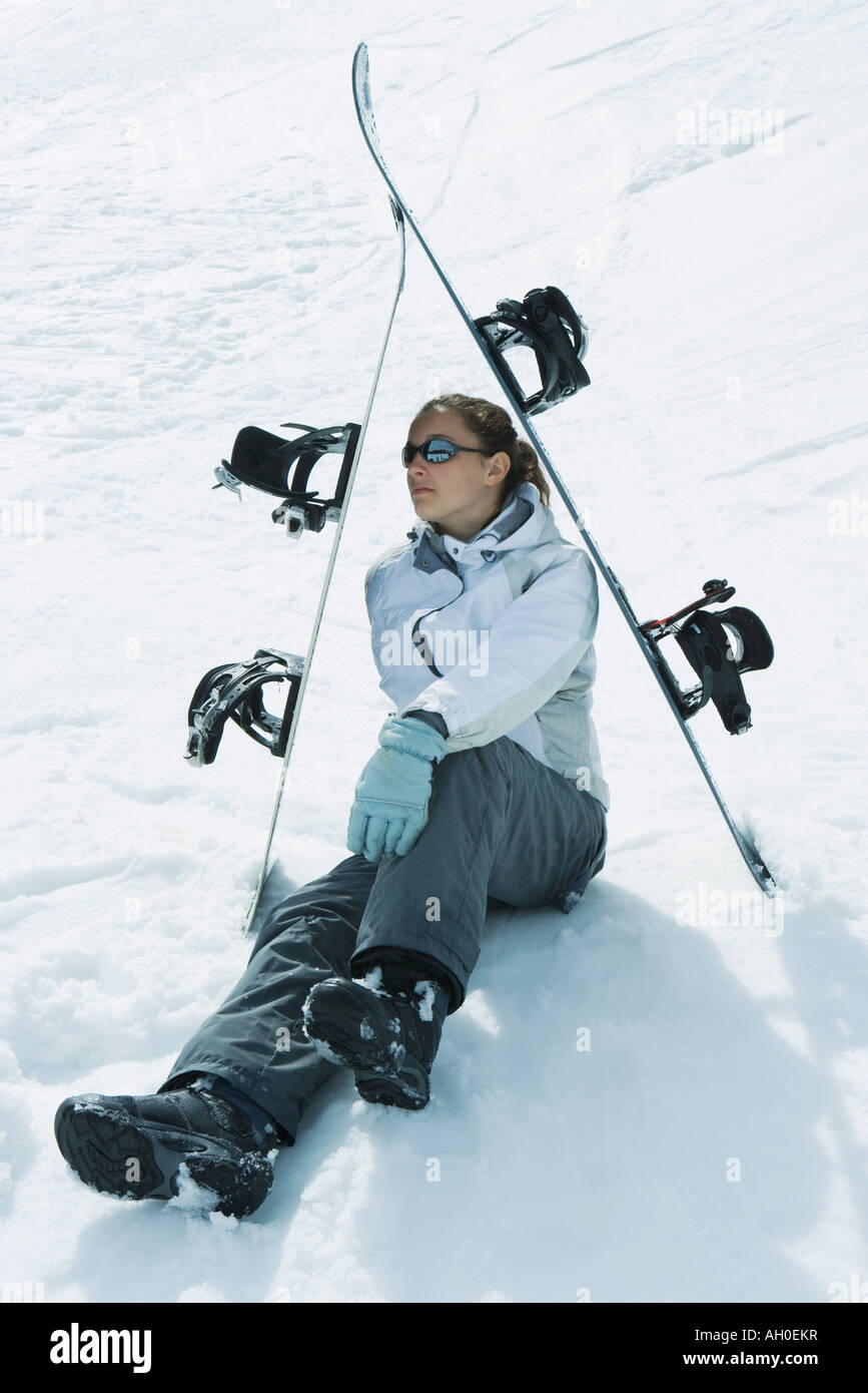 Young female skier sitting on the ground under skis, looking away Stock ...