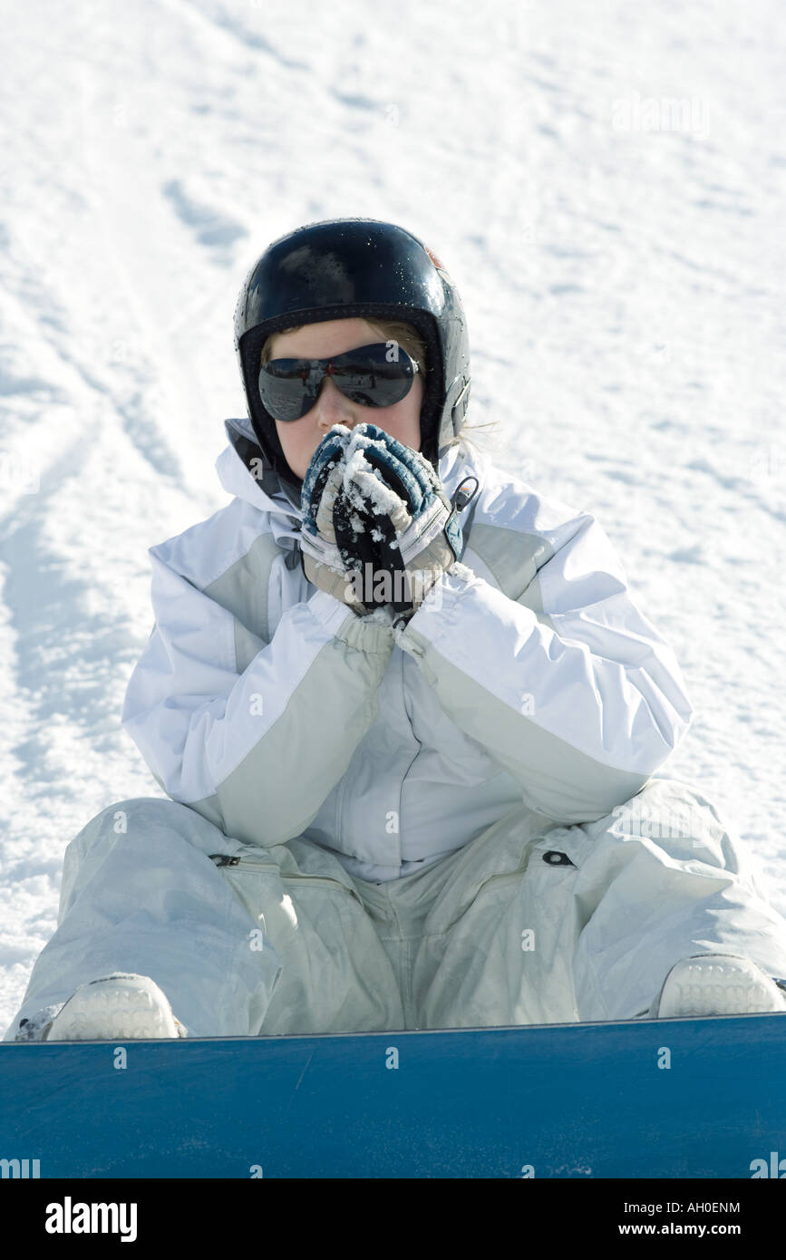 Young snowboarder sitting on ground, clasped hands covering mouth Stock ...