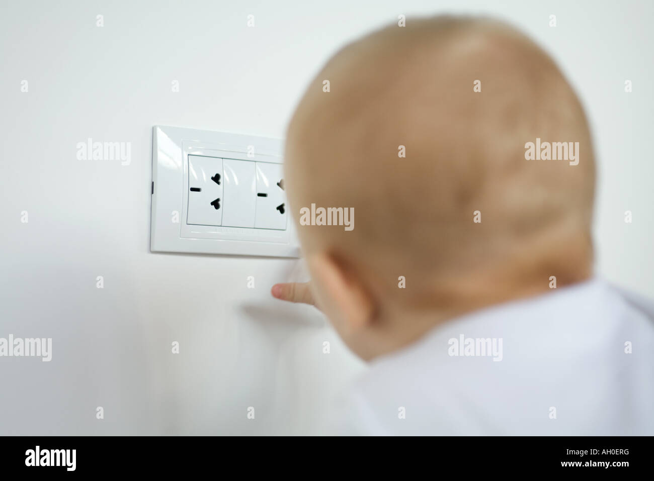 Baby touching electric outlet, rear view Stock Photo - Alamy