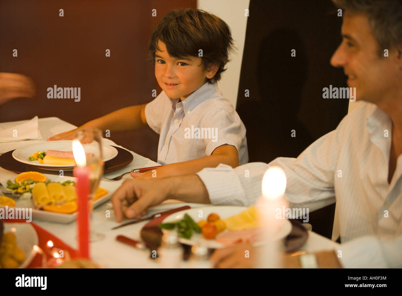 Man and boy sitting at dinner table, smiling Stock Photo - Alamy