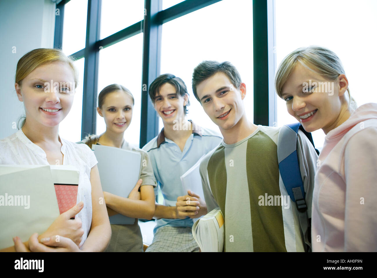 Five students standing in front of window, smiling at camera, group ...