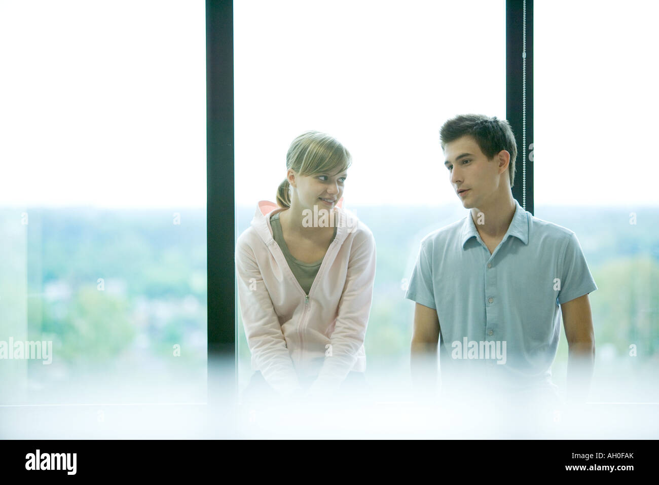 Two young friends chatting in front of window, selective focus Stock ...