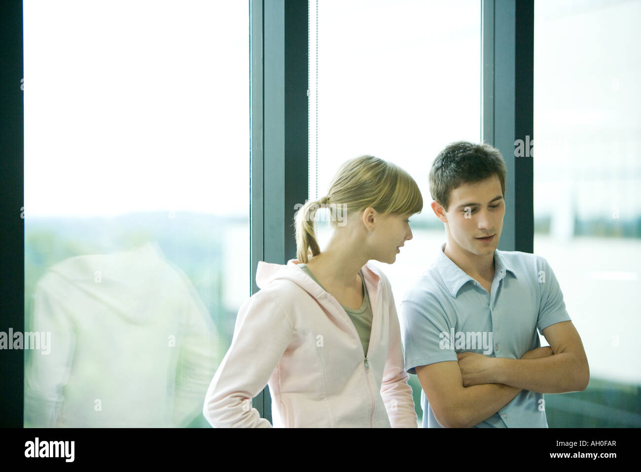 Two young friends side by side in front of window, talking Stock Photo ...