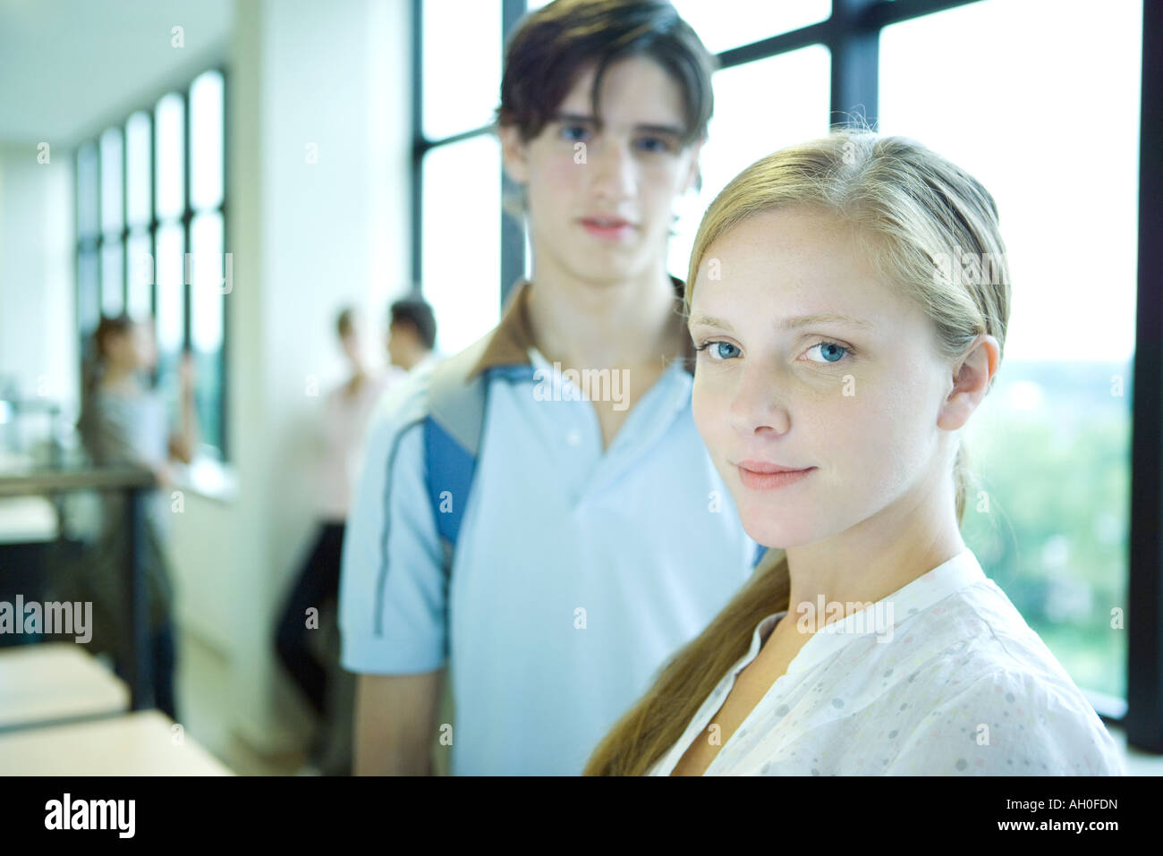 Female student smiling at camera, sideways glance, male peer in ...
