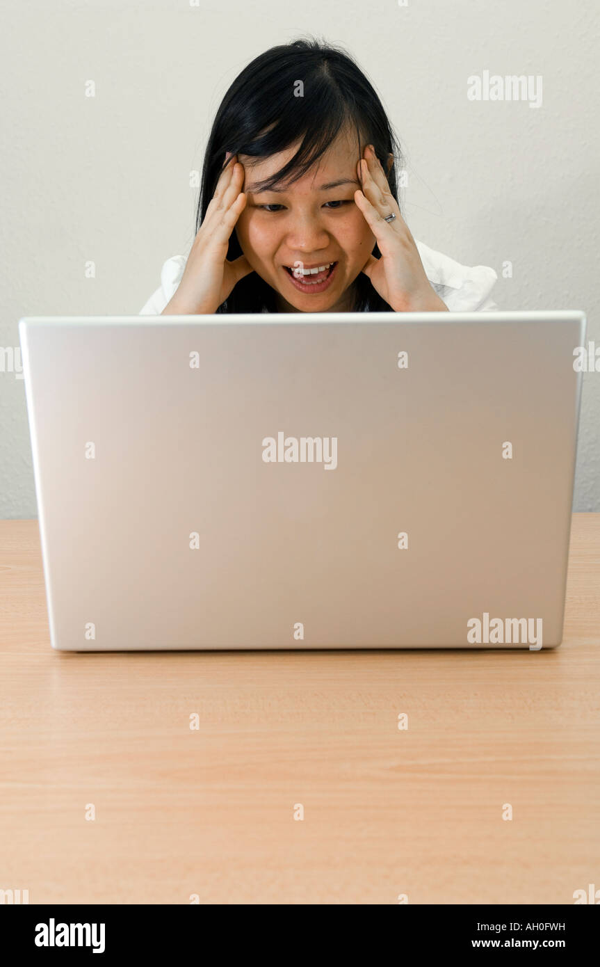 Chinese business woman reading something funny from laptop computer ...