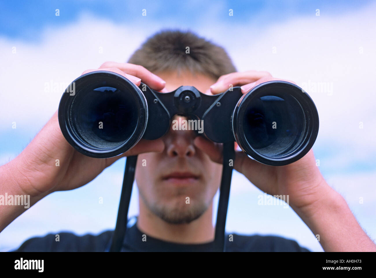"^Young man looking through ^binoculars Stock Photo - Alamy