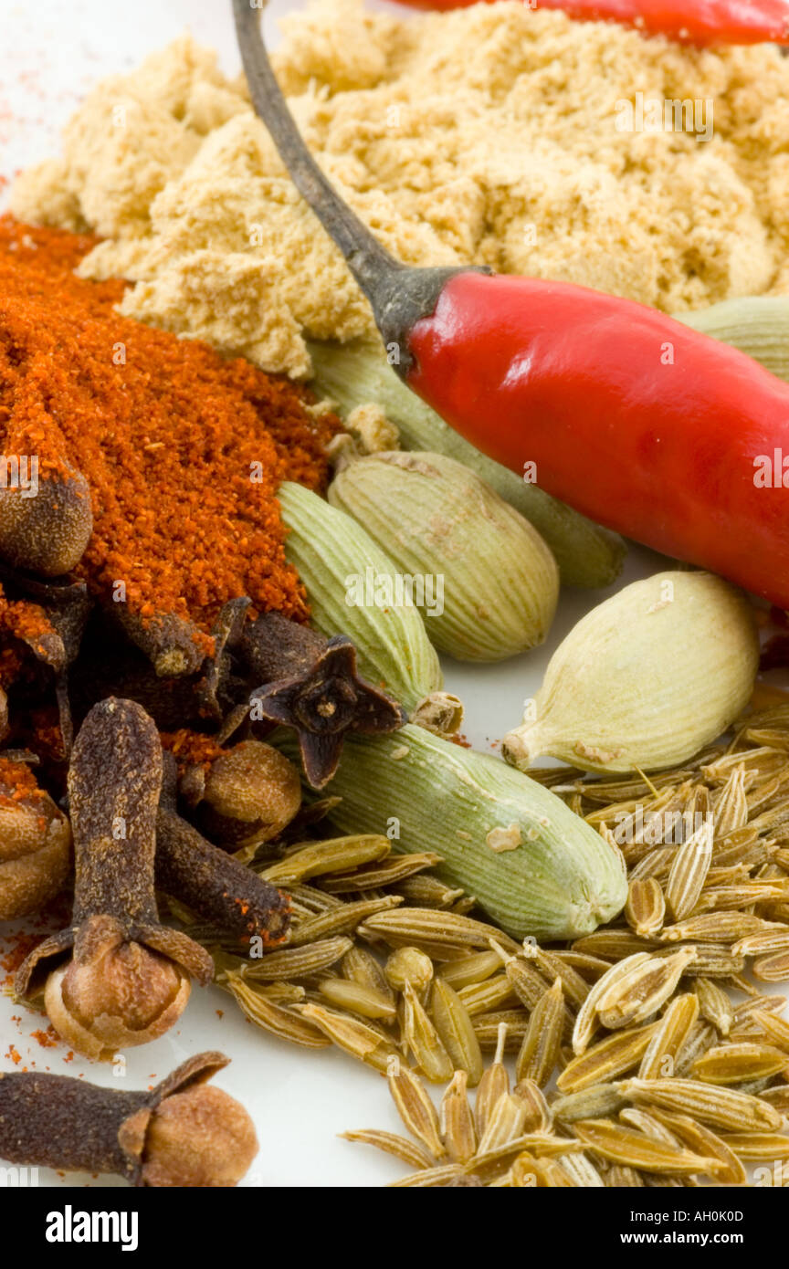 A selection of spices including cardamom pods against a white ...