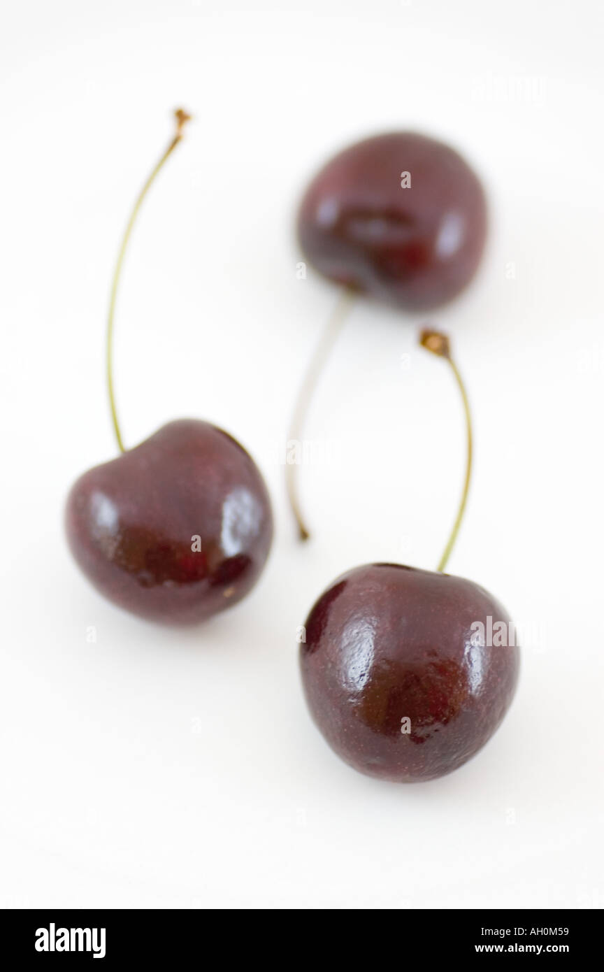 Three cherries against a white background Stock Photo - Alamy
