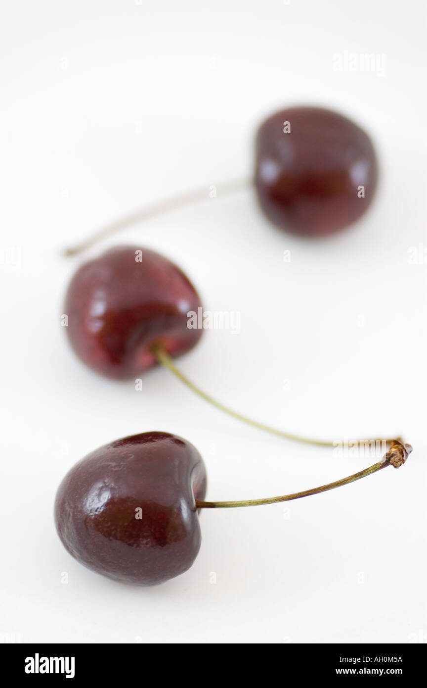 Three cherries against a white background Stock Photo - Alamy