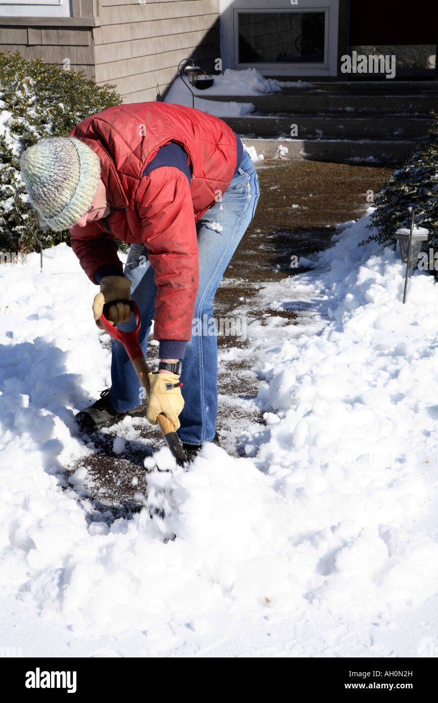 Man bent over using a garden spade to clear front walkway of house ...