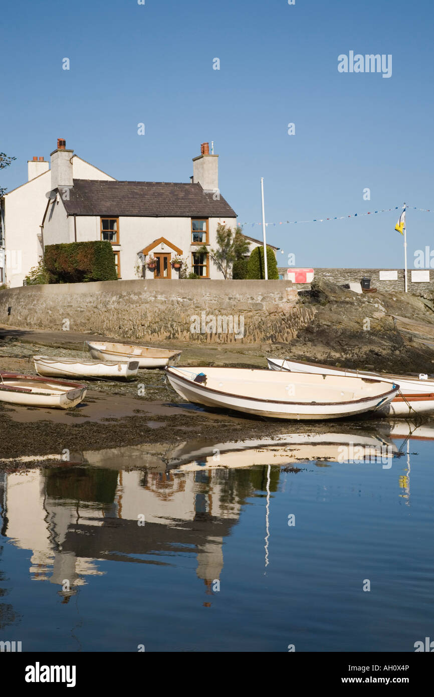Cottage and moored boats reflected in calm harbour sea water in most ...