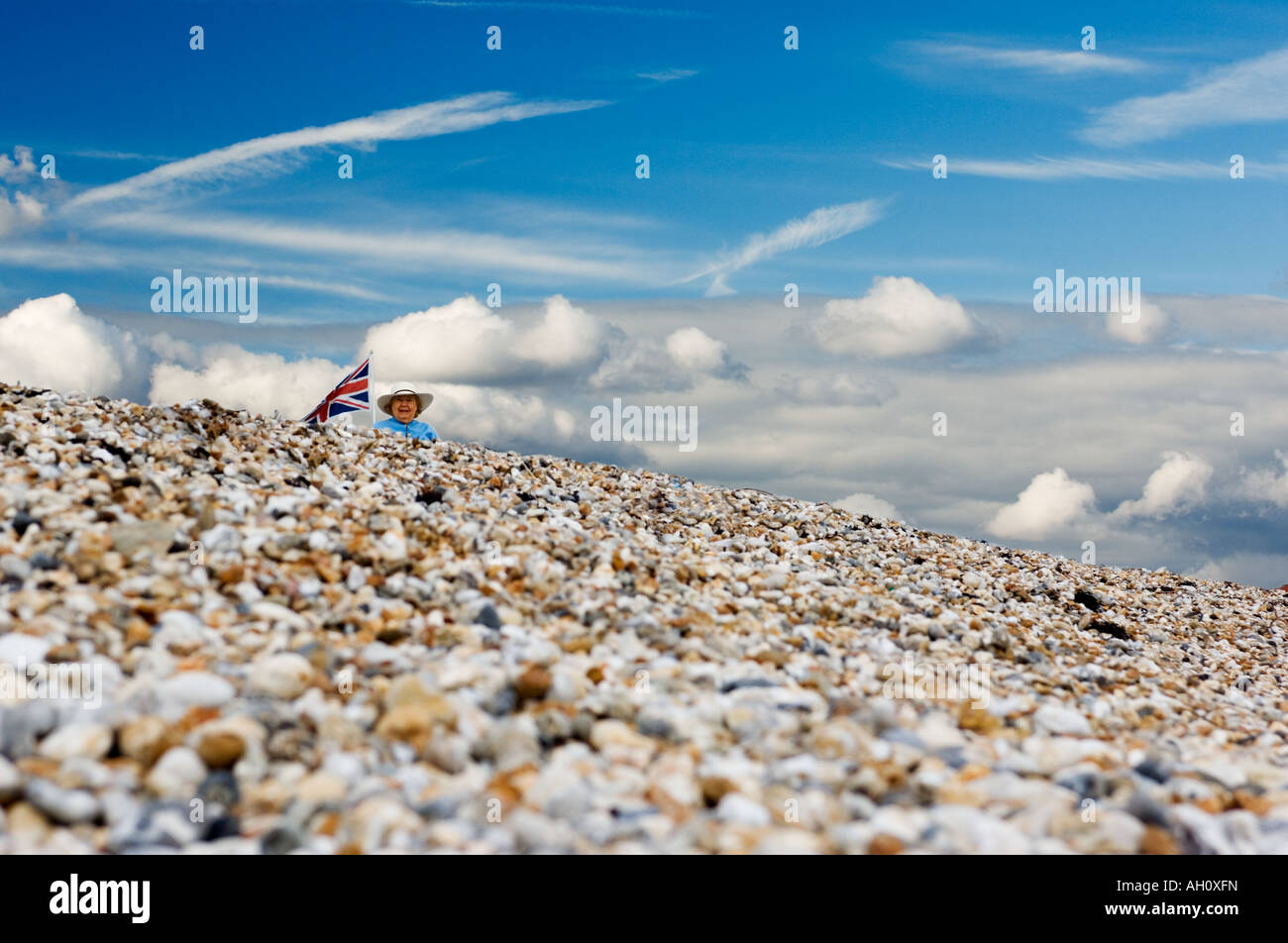 Beach with Union Jack, Lady & shingle with blue sky Stock Photo - Alamy