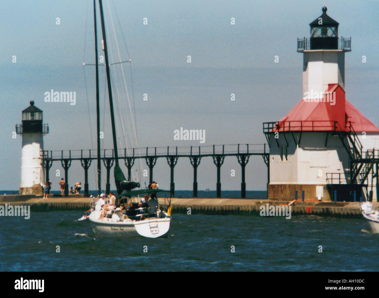 Pier and lighthouses with sailboat heading out to Lake Michigan, on the ...
