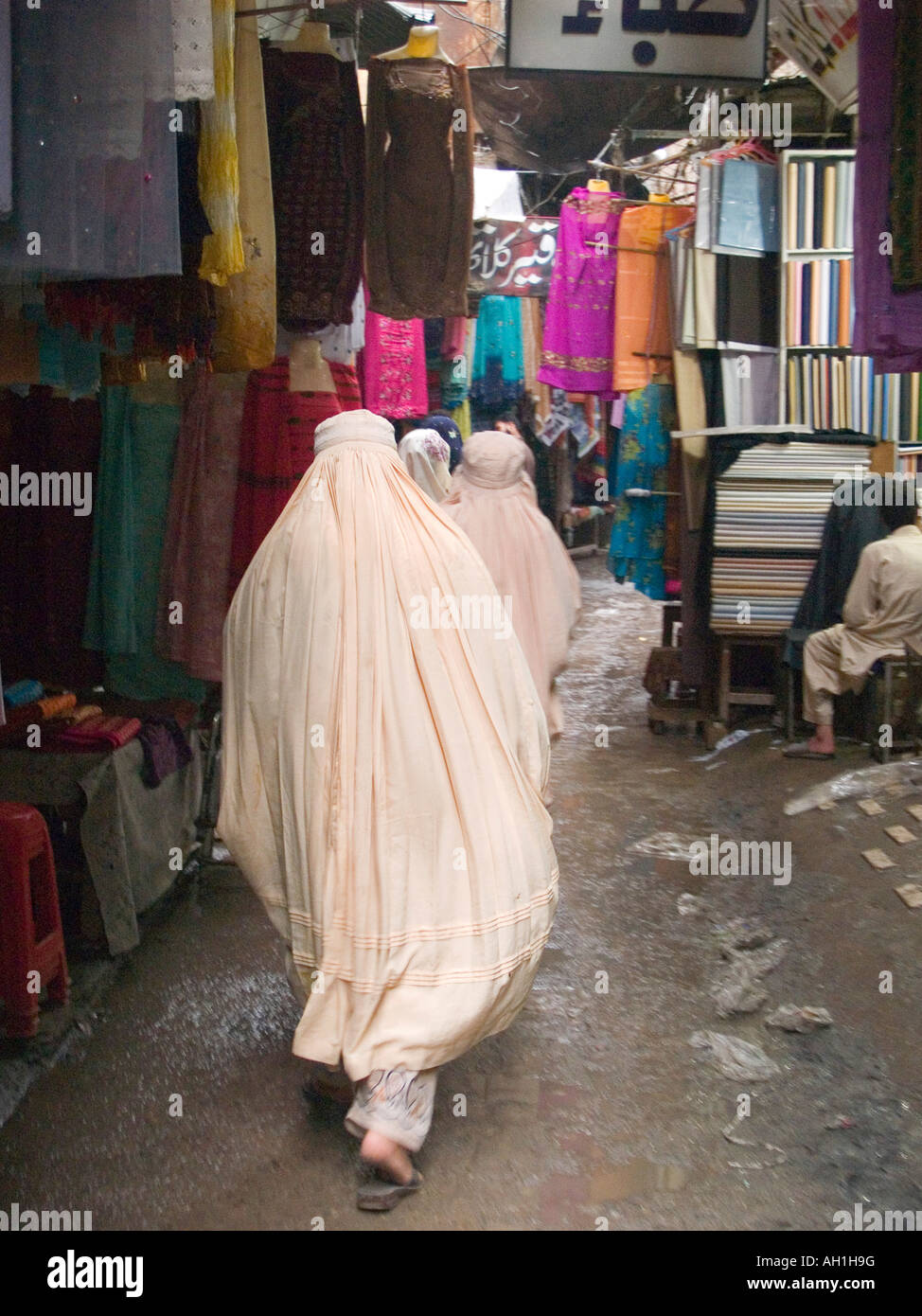 ghostly looking women in burkhas pass through the Peshawar Bazaar ...