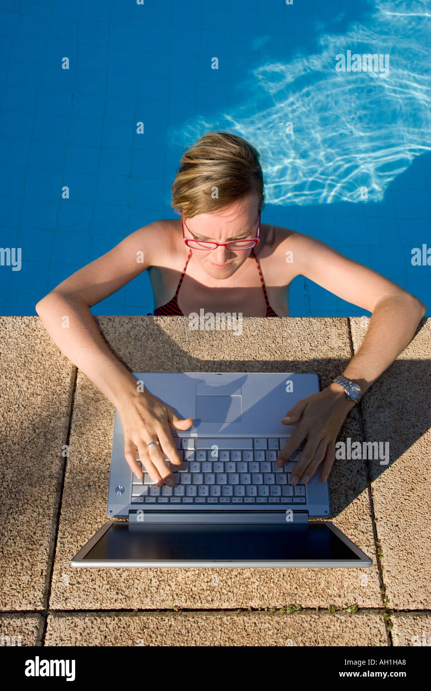 Workaholic lady typing on laptop while on holiday in the pool Stock ...