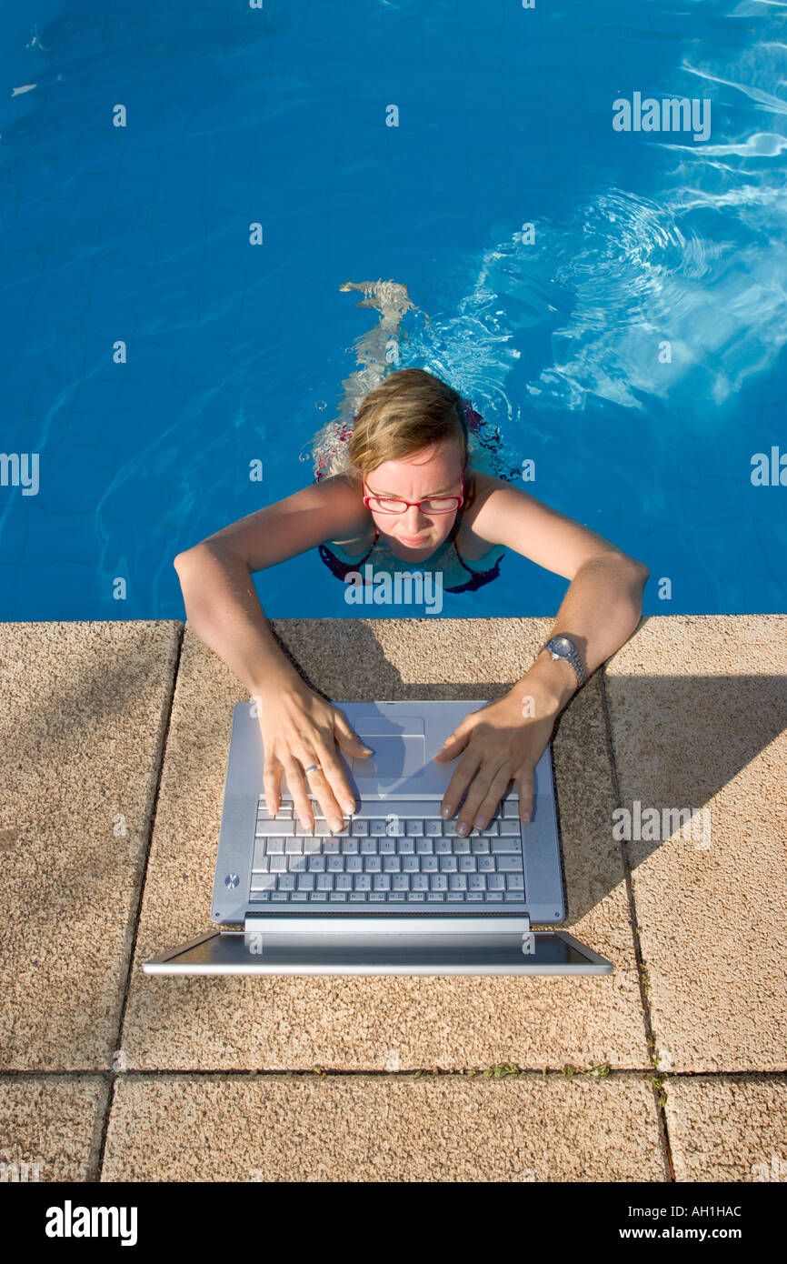 Workaholic lady typing on laptop while on holiday in the pool Stock ...