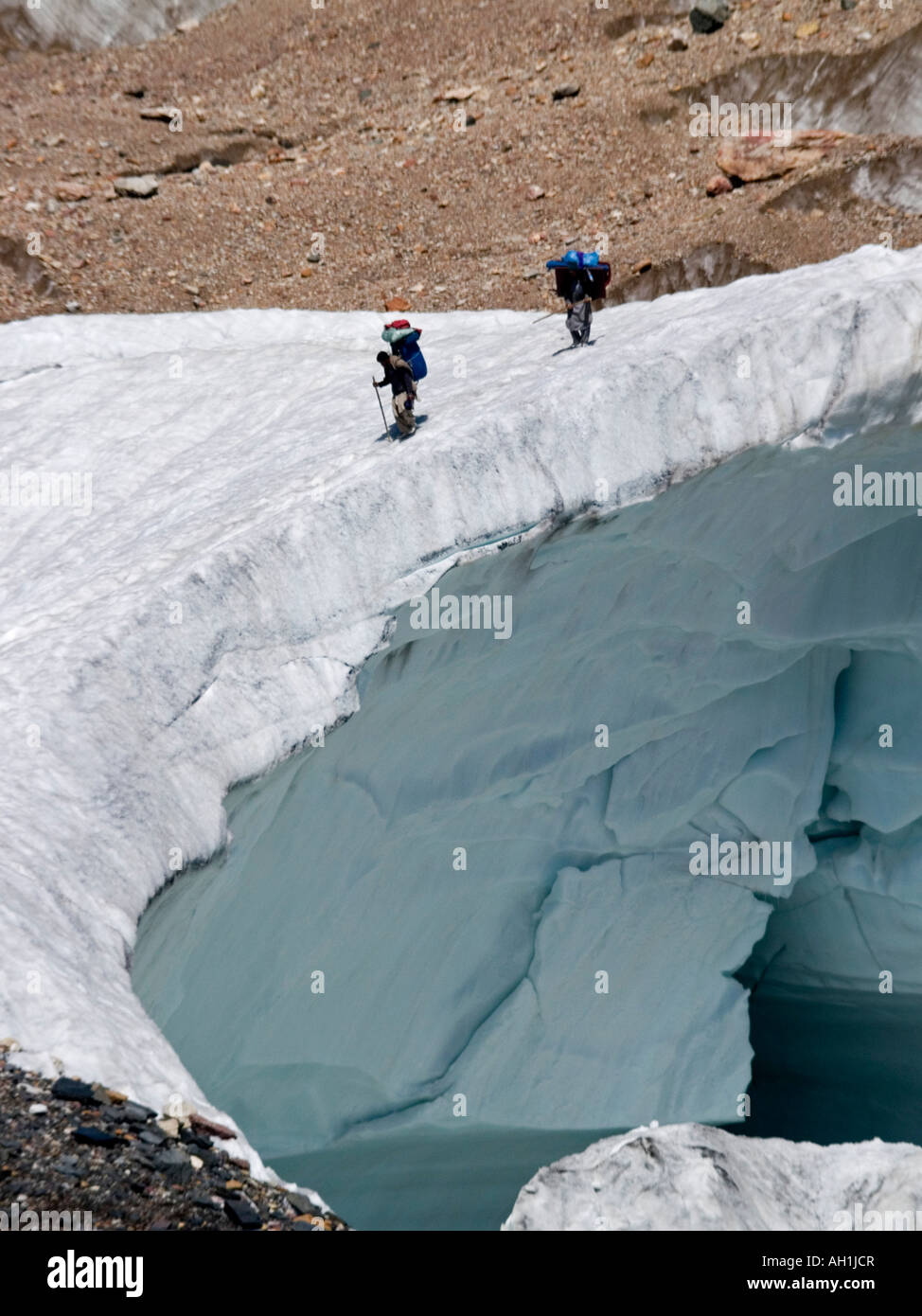 Porters walk a snow bridge over giant crevasses on the way from K2 Base ...