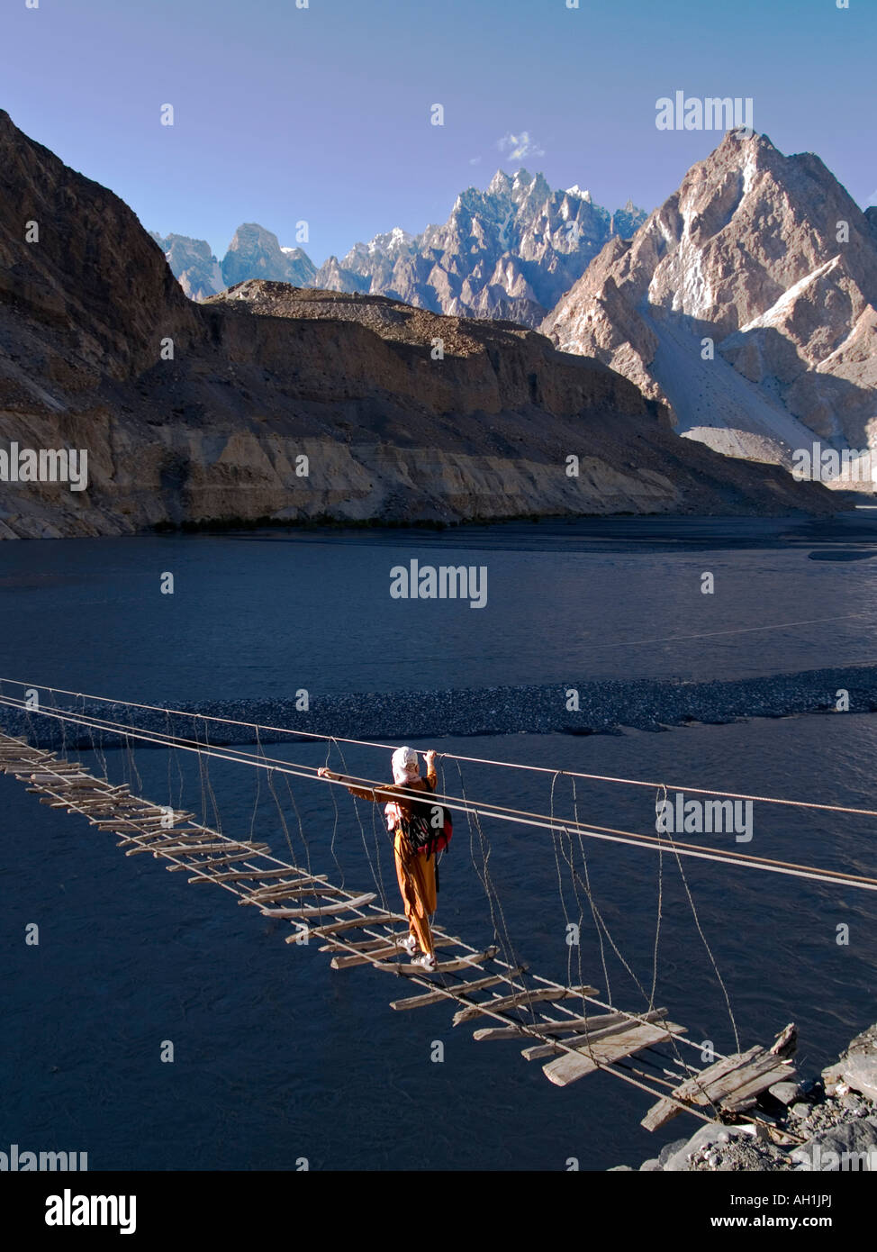 trekker makes the crossing of the Hunza River in the Karakoram ...