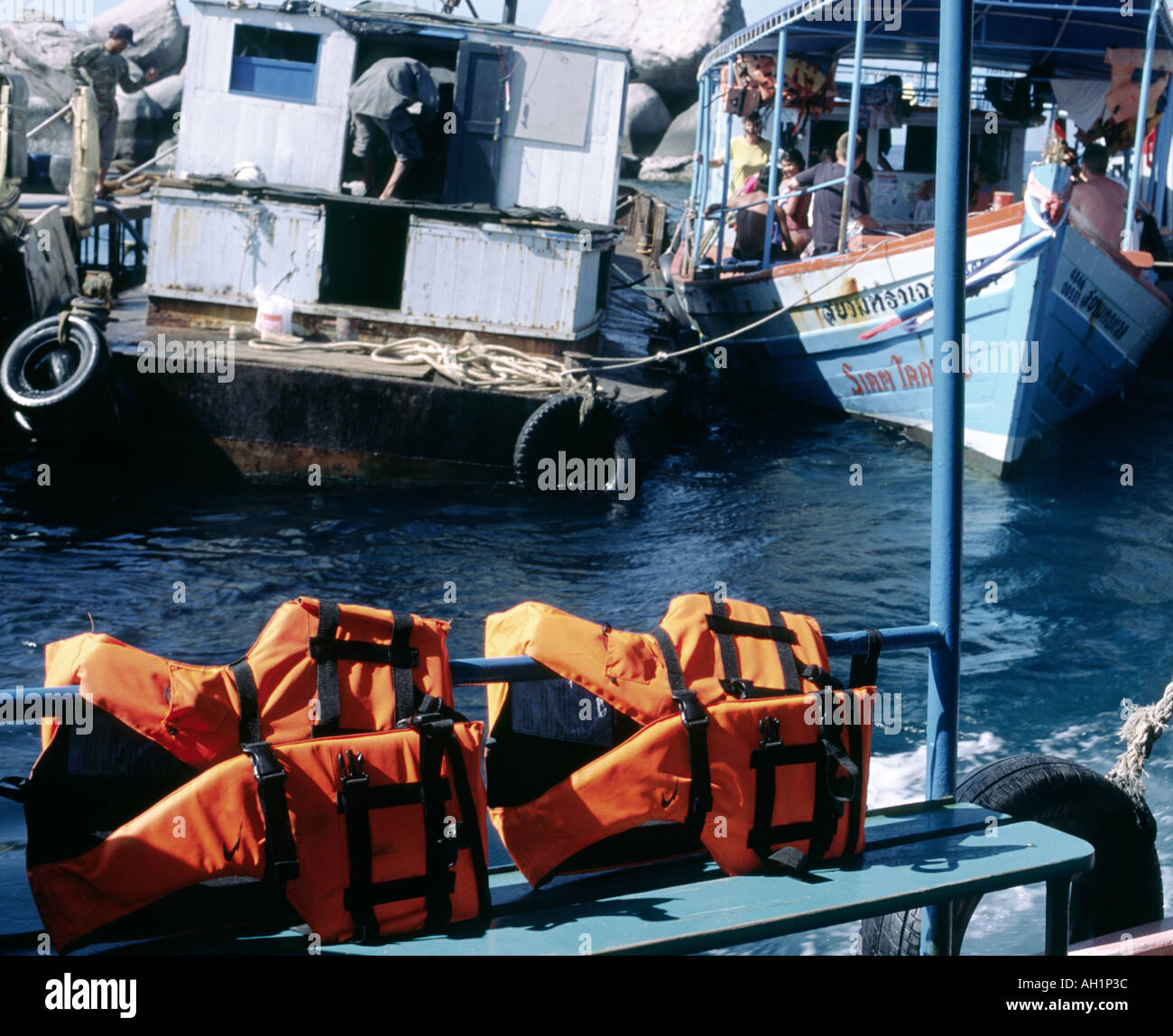 Bright orange life jacket flotation devises on the bench of a tourist ...