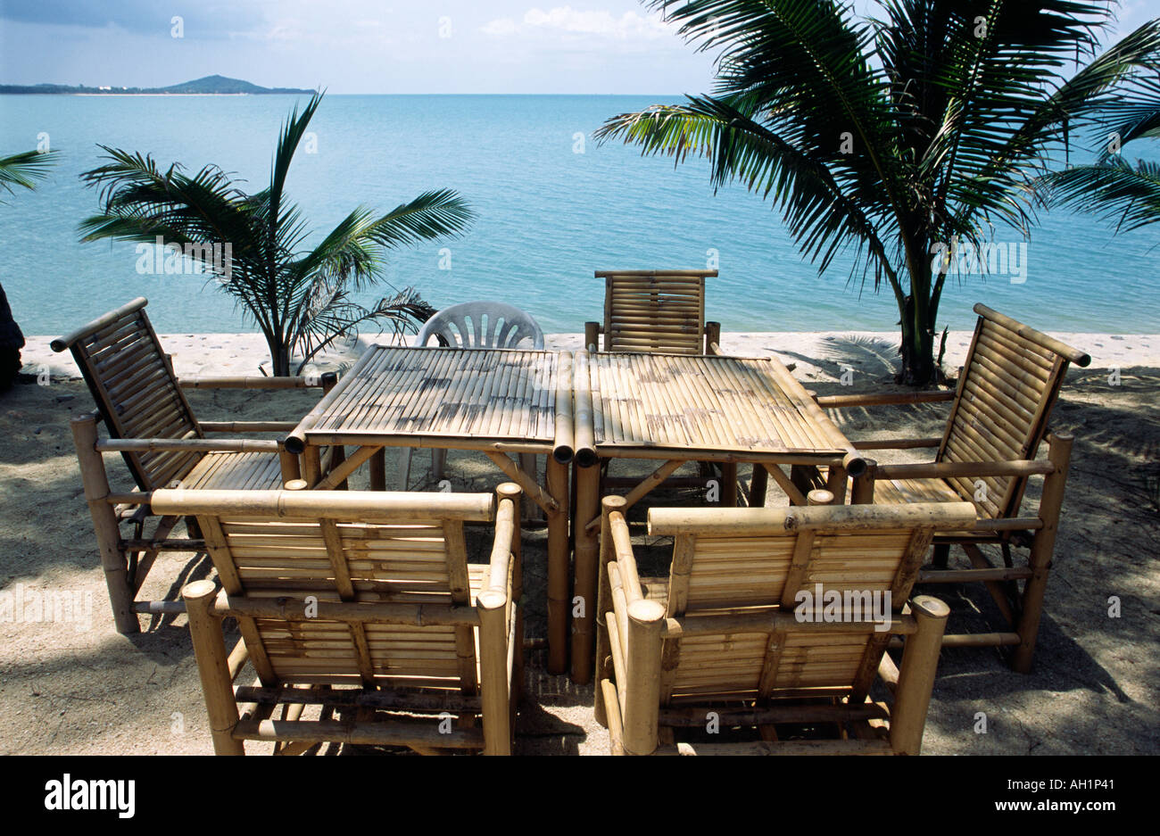 Thatched wood bamboo outdoor table and chairs on the beach among the ...