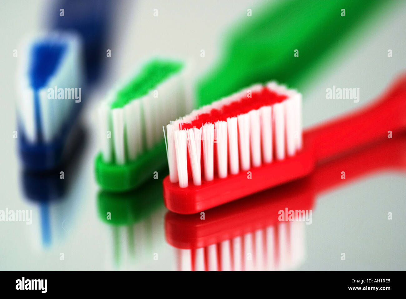 Red green and blue toothbrushes on a mirror with their reflections ...