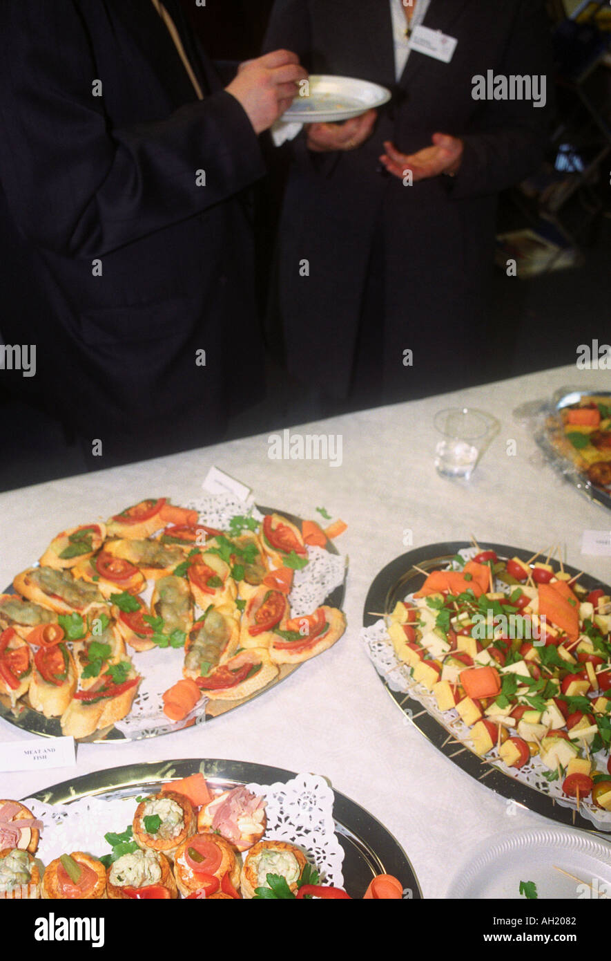 Plates of canapes with visitors talking at a book launch, London, UK ...