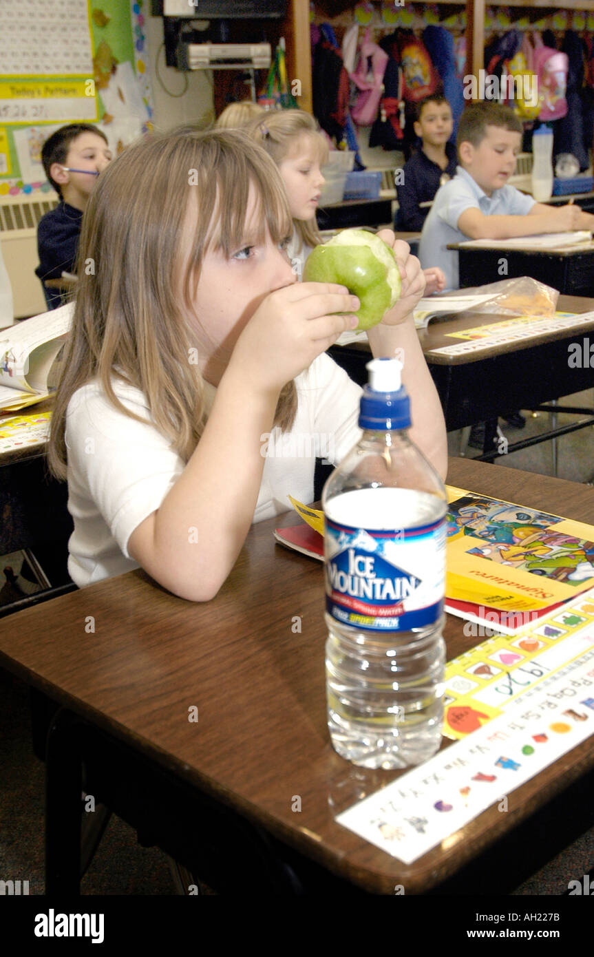 Elementary student girl eating apple with bottled water Stock Photo - Alamy