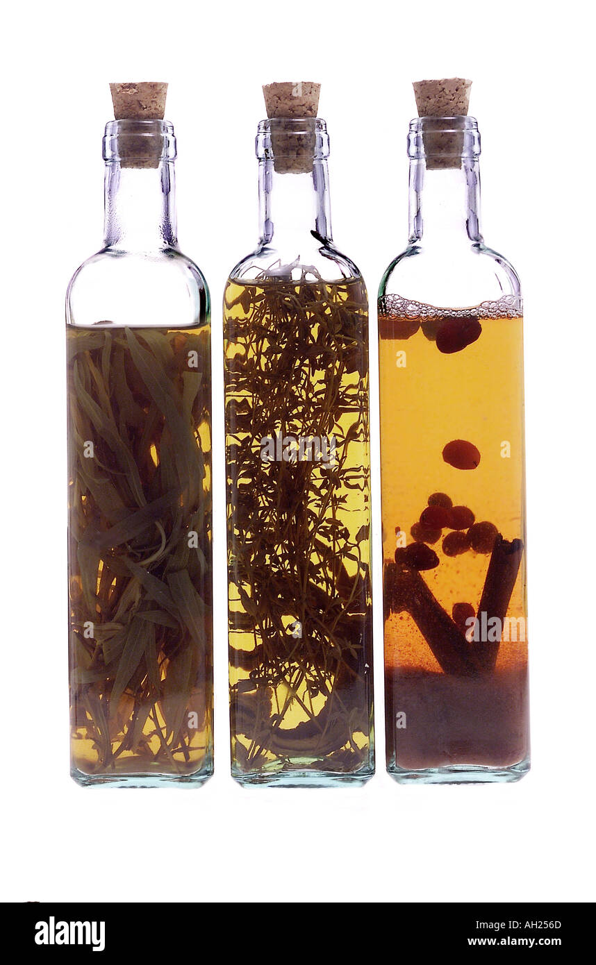 three bottles of vinegar with herbs and spices silhouetted on white ...