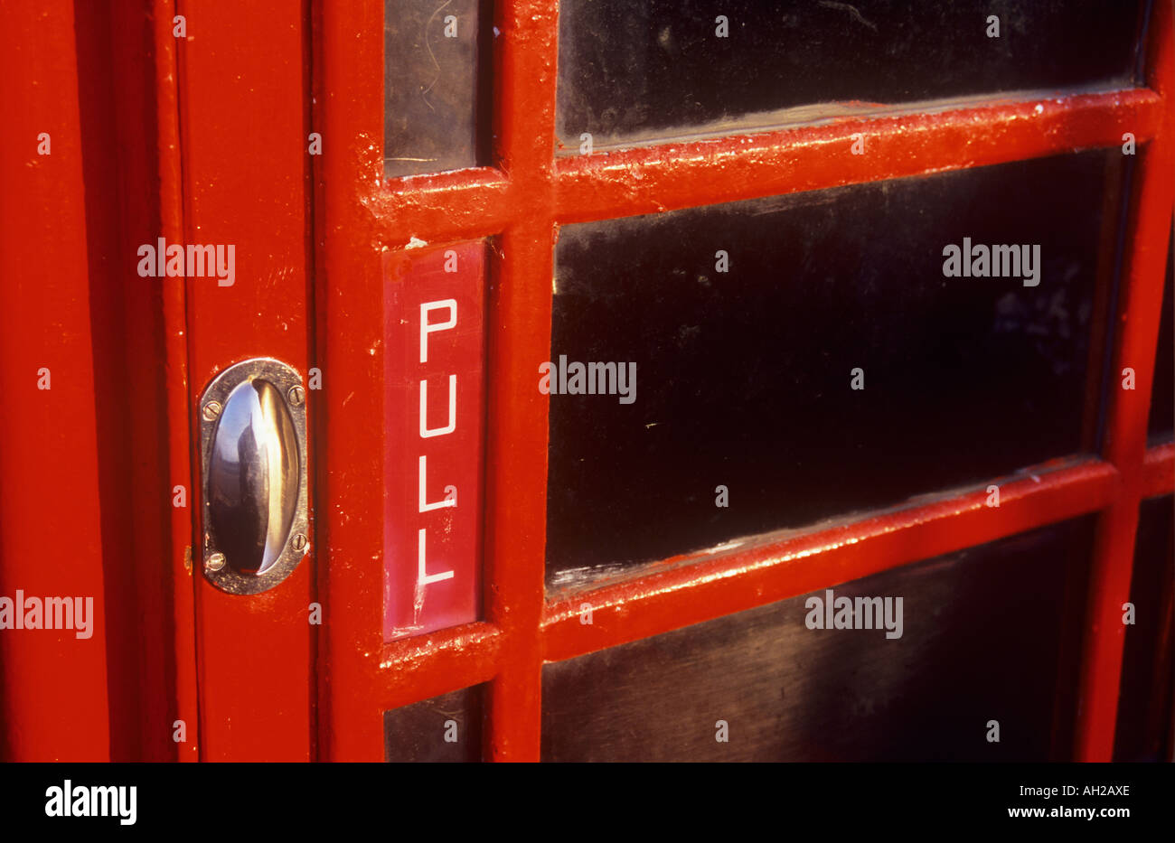 Detail of the door of an old style UK red phone box with windows silver ...