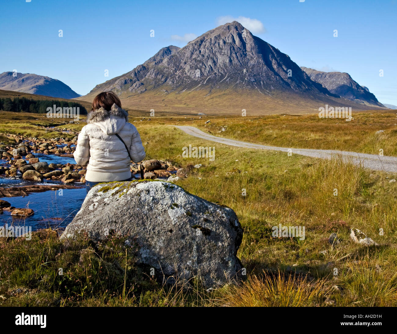Woman sitting on a rock admiring the scenery of Rannoch Moor and ...