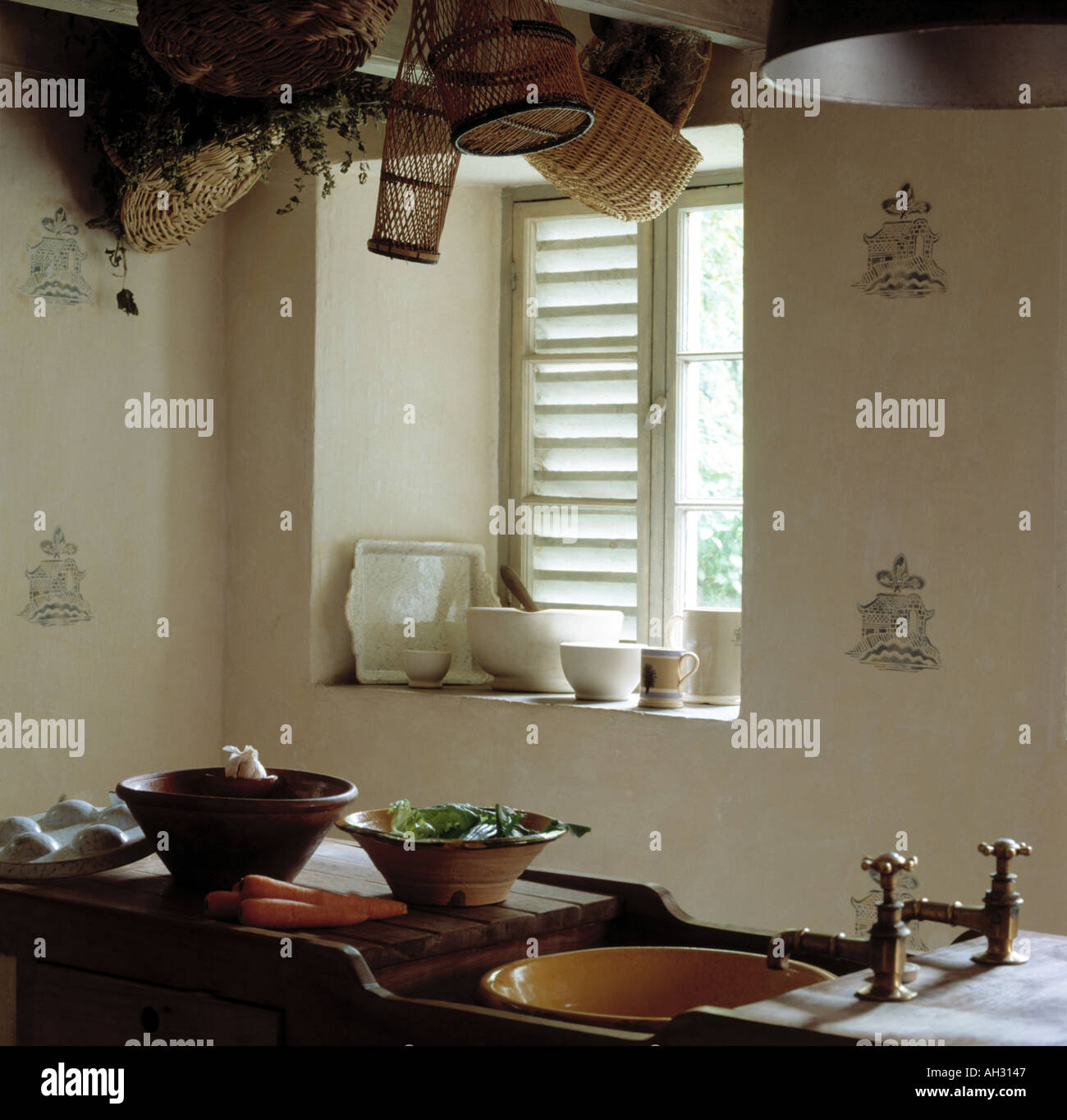 White louvre shutter on window in country kitchen with vegetables in ...