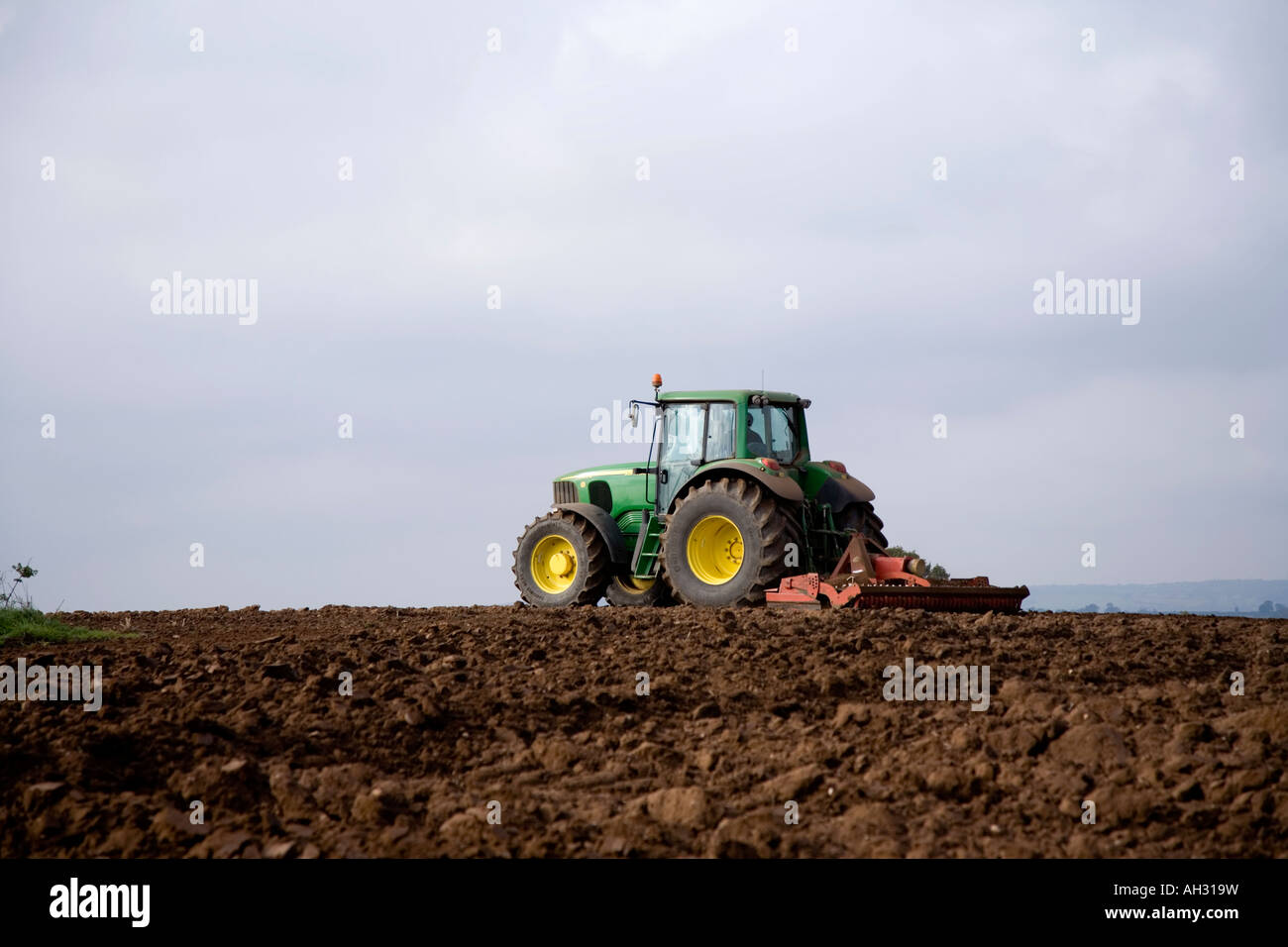 Tractor disc harrowing a field Stock Photo - Alamy