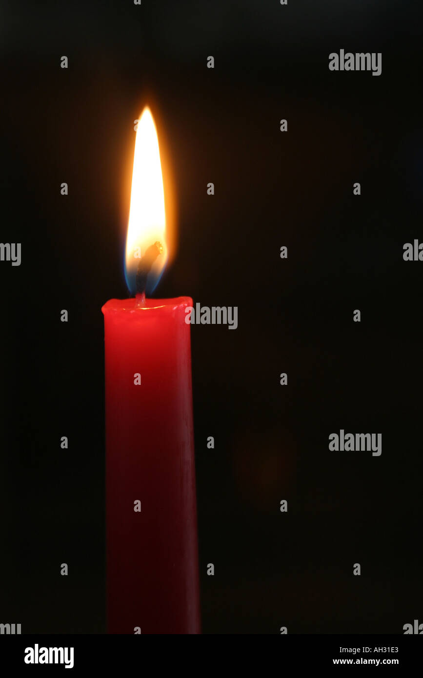 Red candle lit against black background Stock Photo - Alamy
