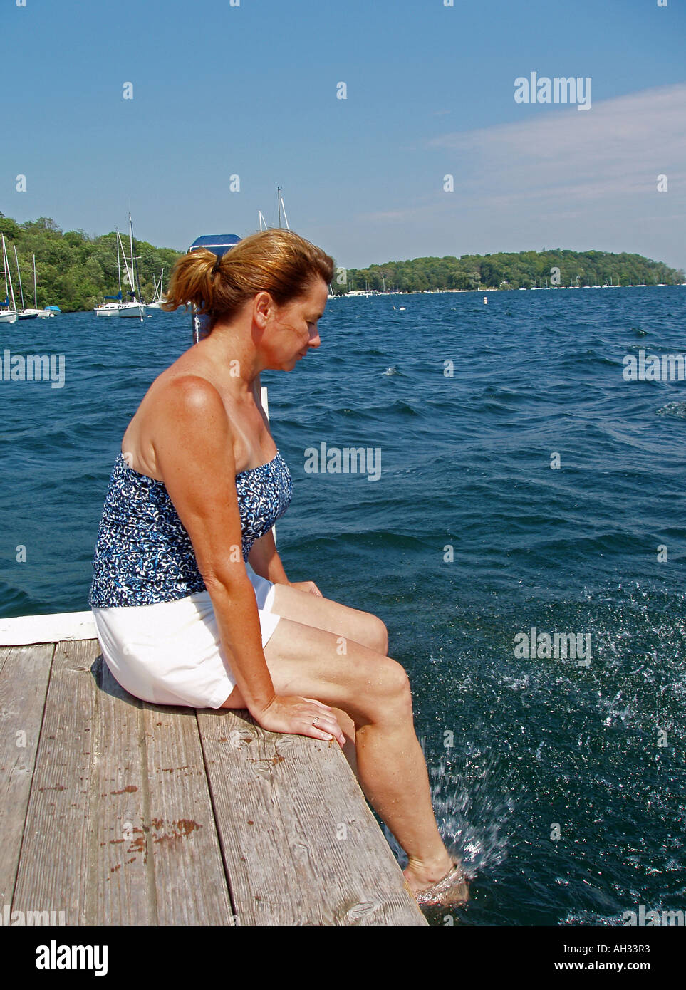 Girl Dangling legs off Dock Stock Photo - Alamy