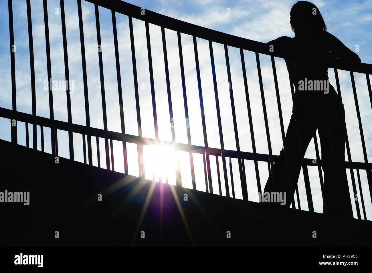 Sillouette of a woman behind railings with strong sunlight Stock Photo ...