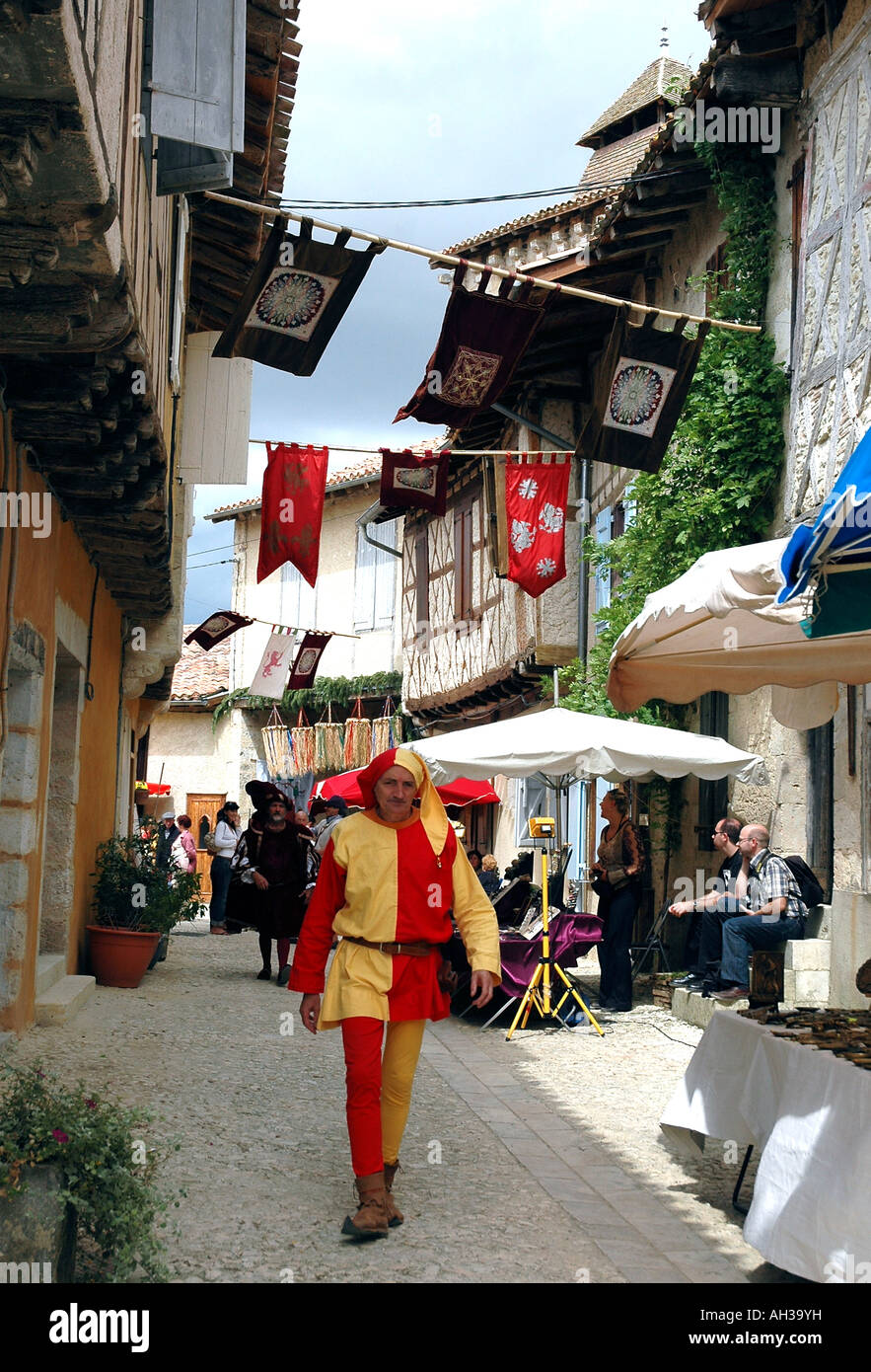 In jester costume a villager parades under courtly banners during a ...