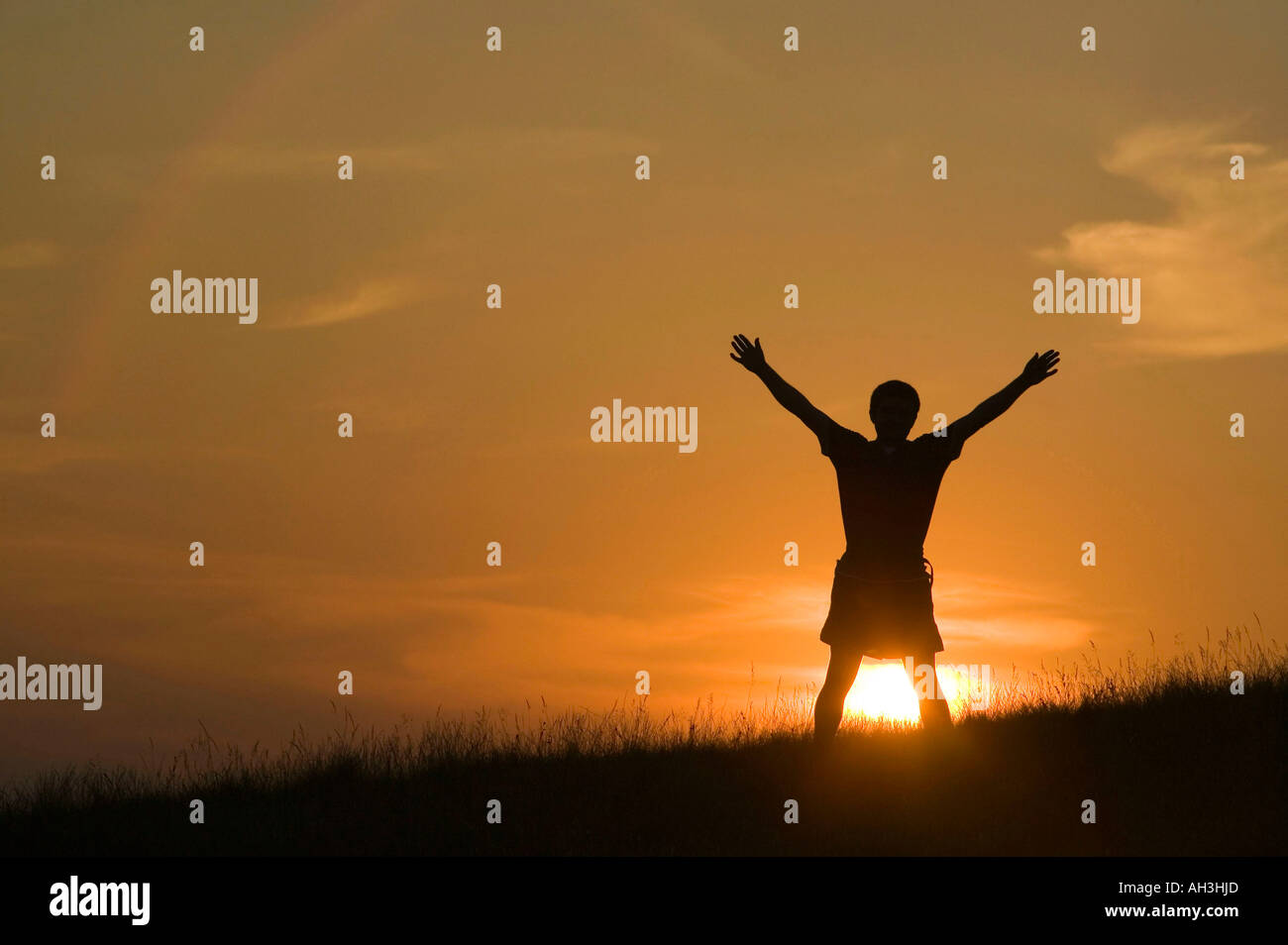 a hill walker celebrates on Helvellyn at sunset, Lake District, UK ...