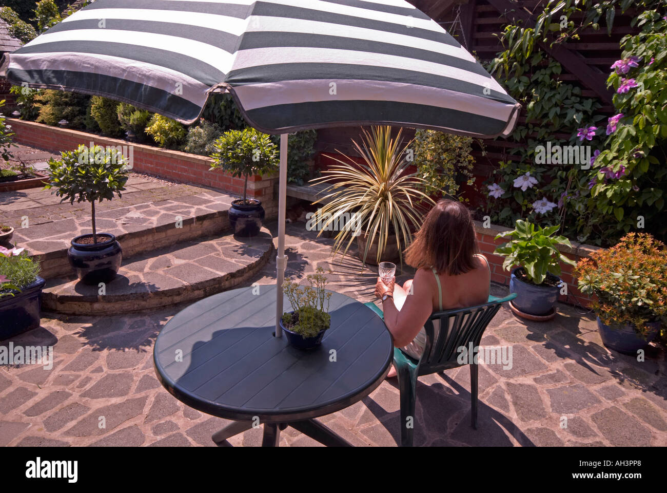 Female sits on patio on a summers day drinking wine Stock Photo - Alamy