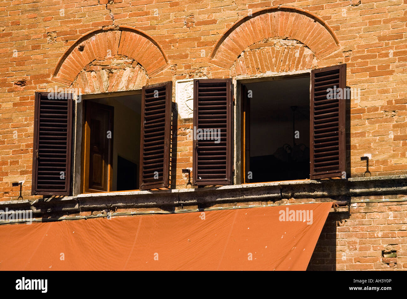 Two arched open shuttered windows with awning, Pienza, Tuscany, Italy ...
