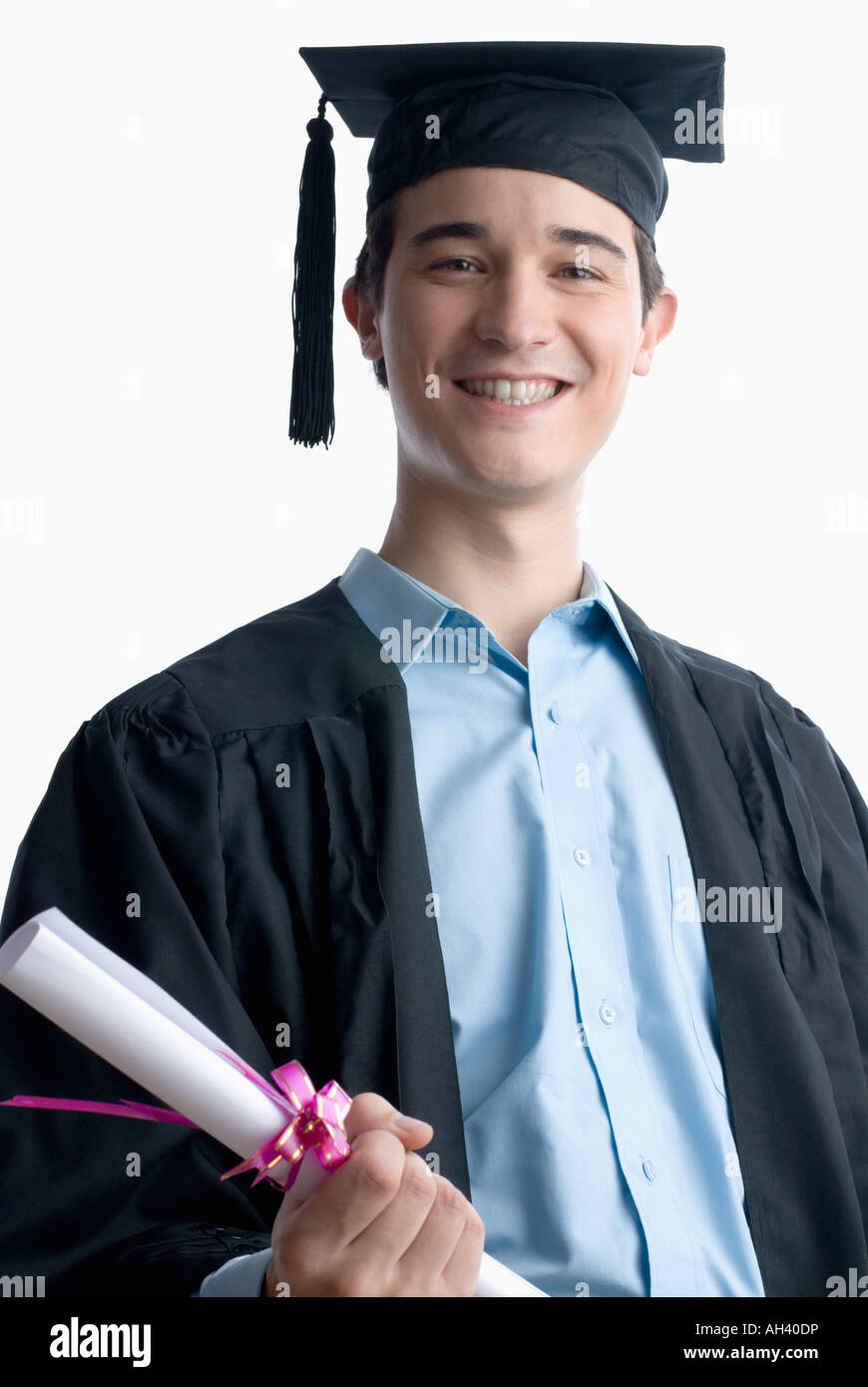 Portrait of a young man in a graduation gown holding a diploma and ...