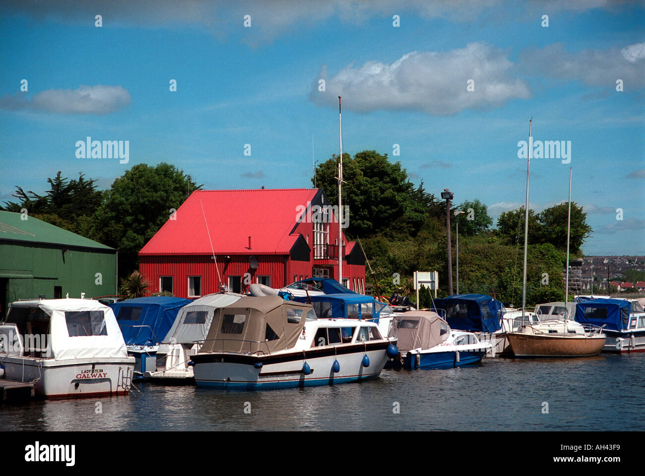 Sunny day scene along Galway River with intensely red boathouse Galway ...