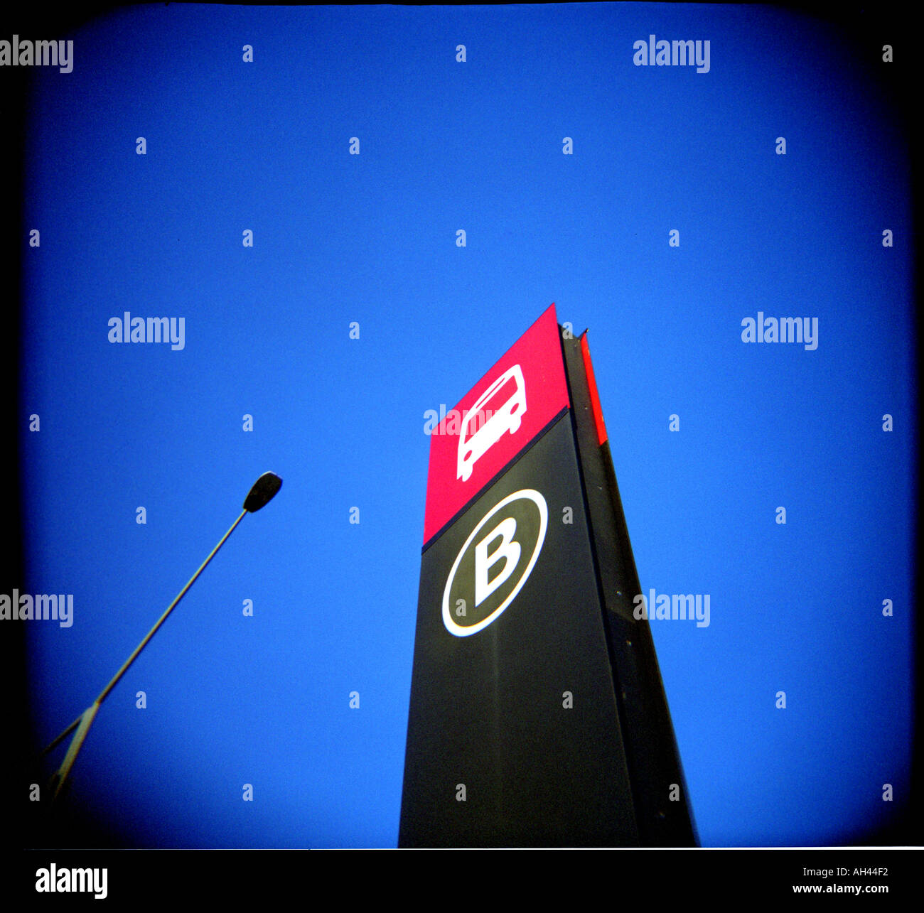 Bright red bus stop sign and a street light on a clear sunny day with ...