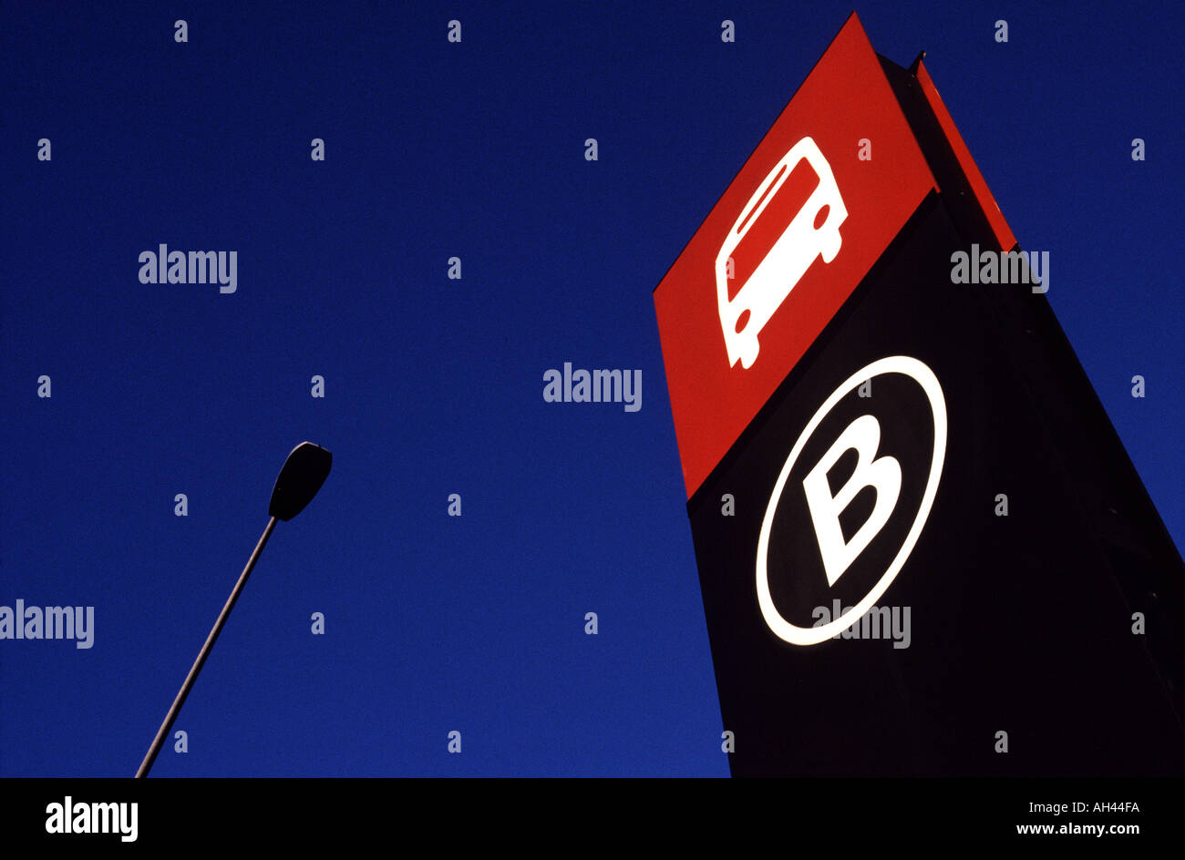 Bright red bus stop sign and a street light on a clear sunny day with ...