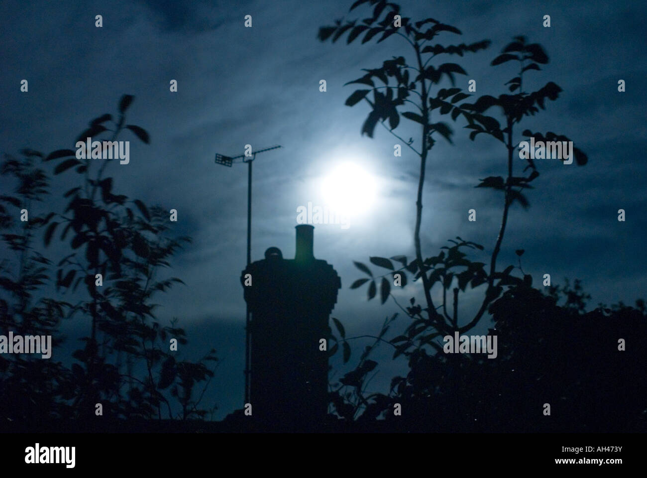 Silouetted Chimney with TV Aerial backlit by full moon with Trees ...